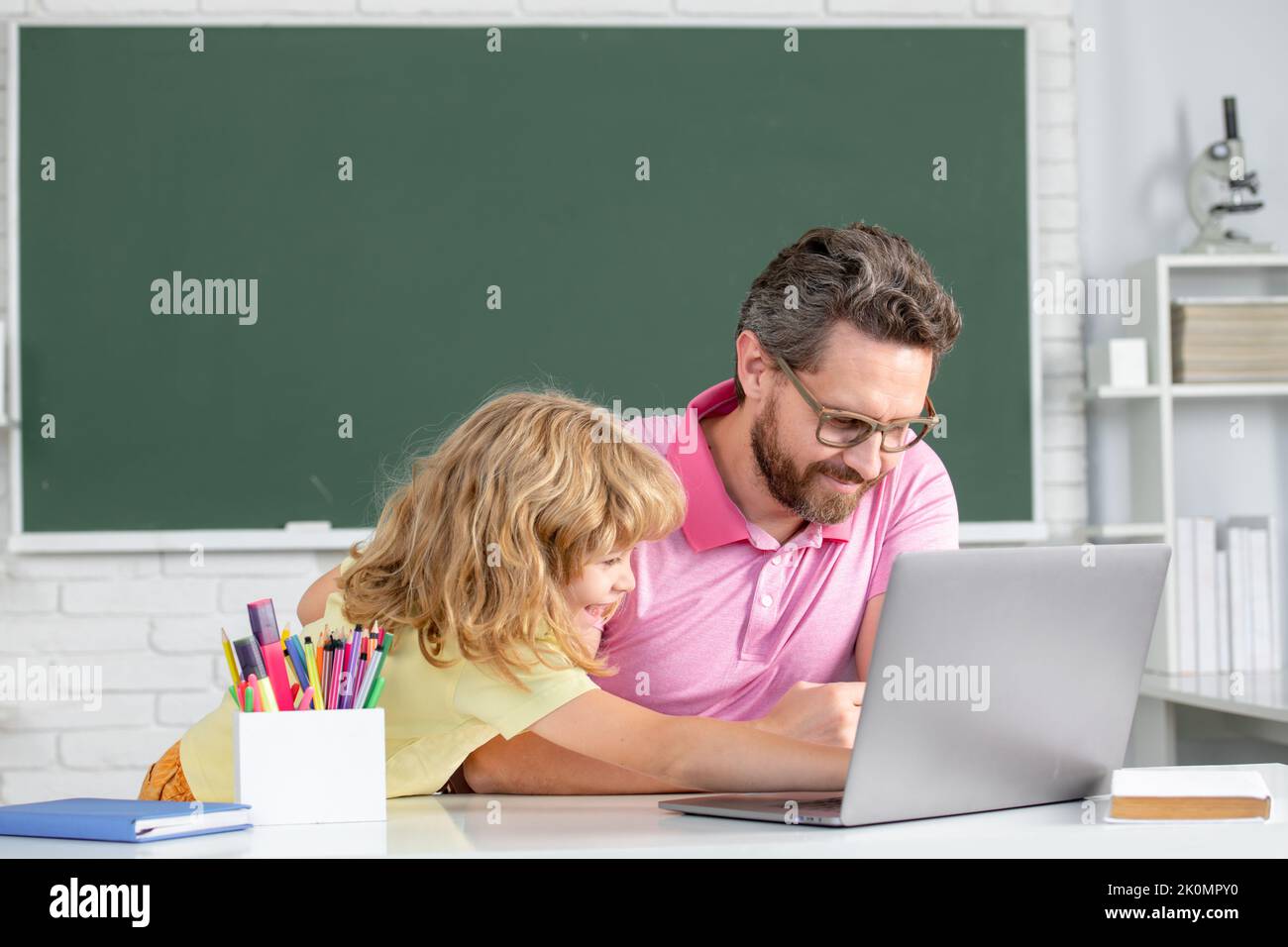 Teacher helping child student pupil from elementary school in classroom ...
