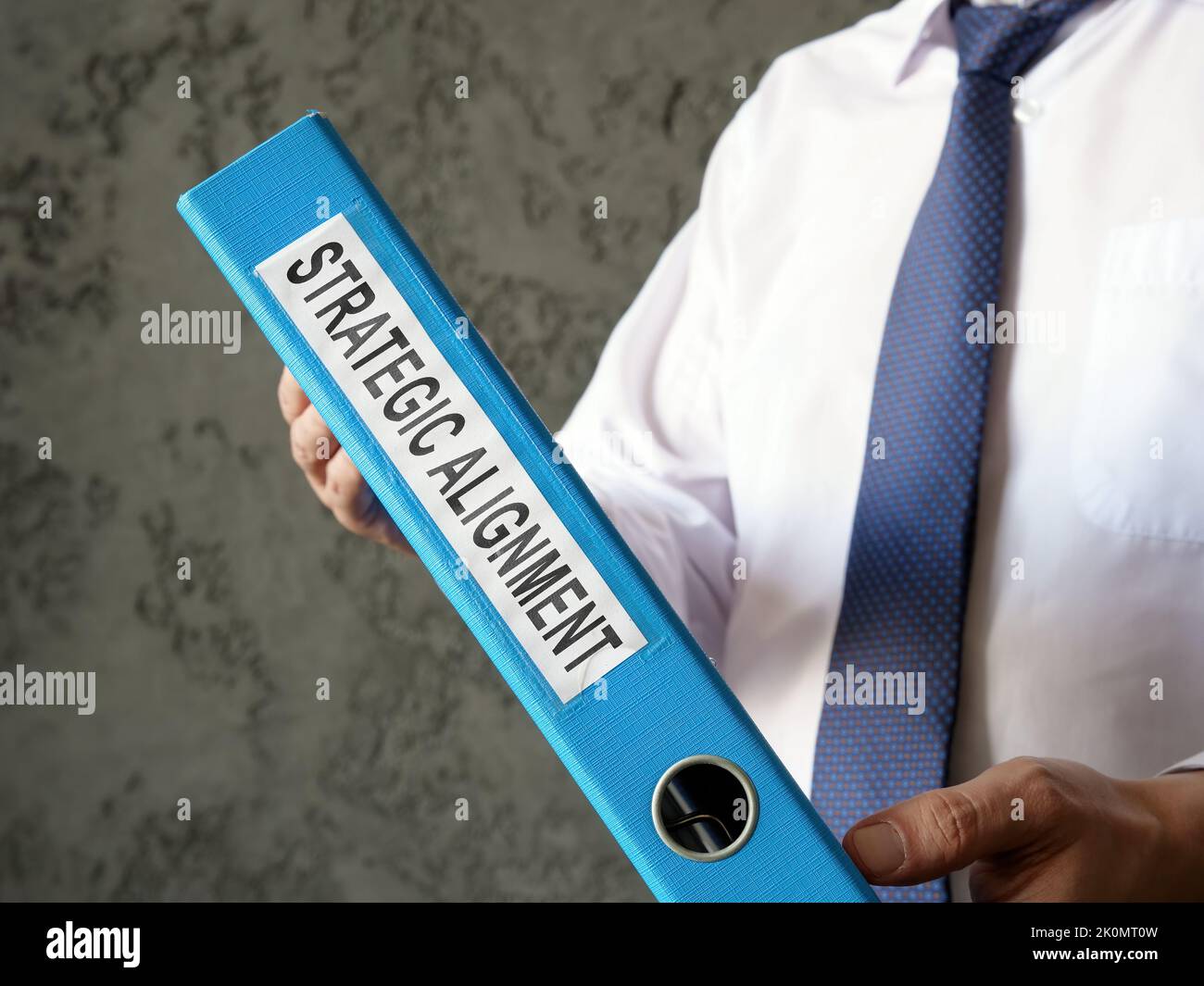 Manager holds blue folder with Strategic alignment Stock Photo - Alamy