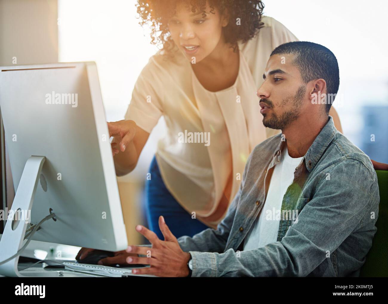 Tweaking their project. designers talking together at a workstation in ...