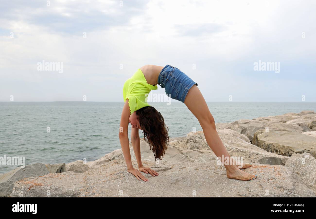 athletic slender girl performing gymnastic exercises arching her back ...
