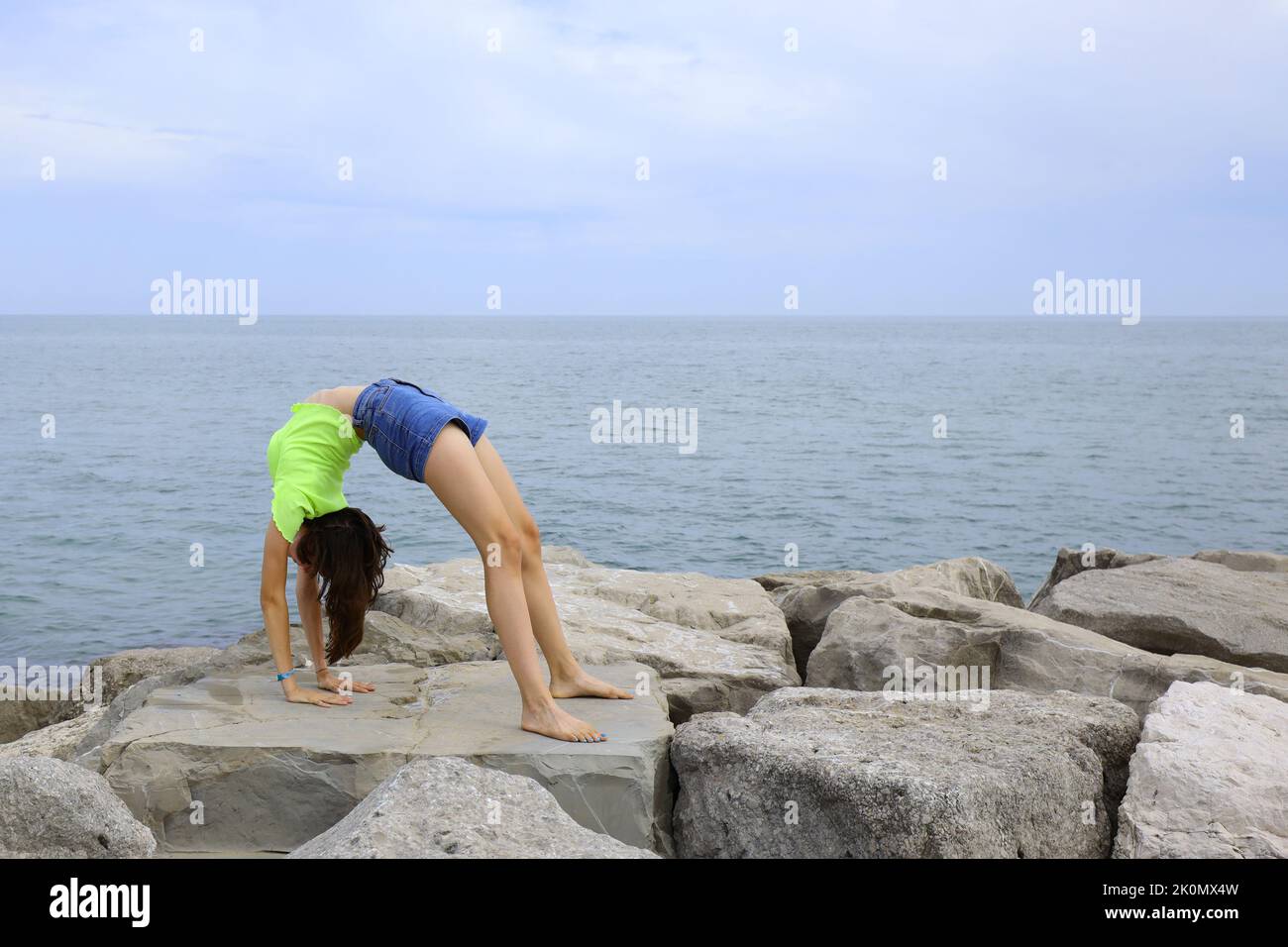 Slender and flexible jointed girl performs an exercise called bendback ...