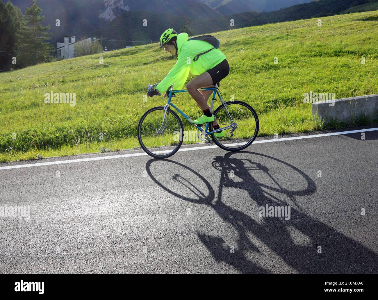 young cyclist with racing bicycle and phosphorescent waterproof jacket on a mountain road Stock ...