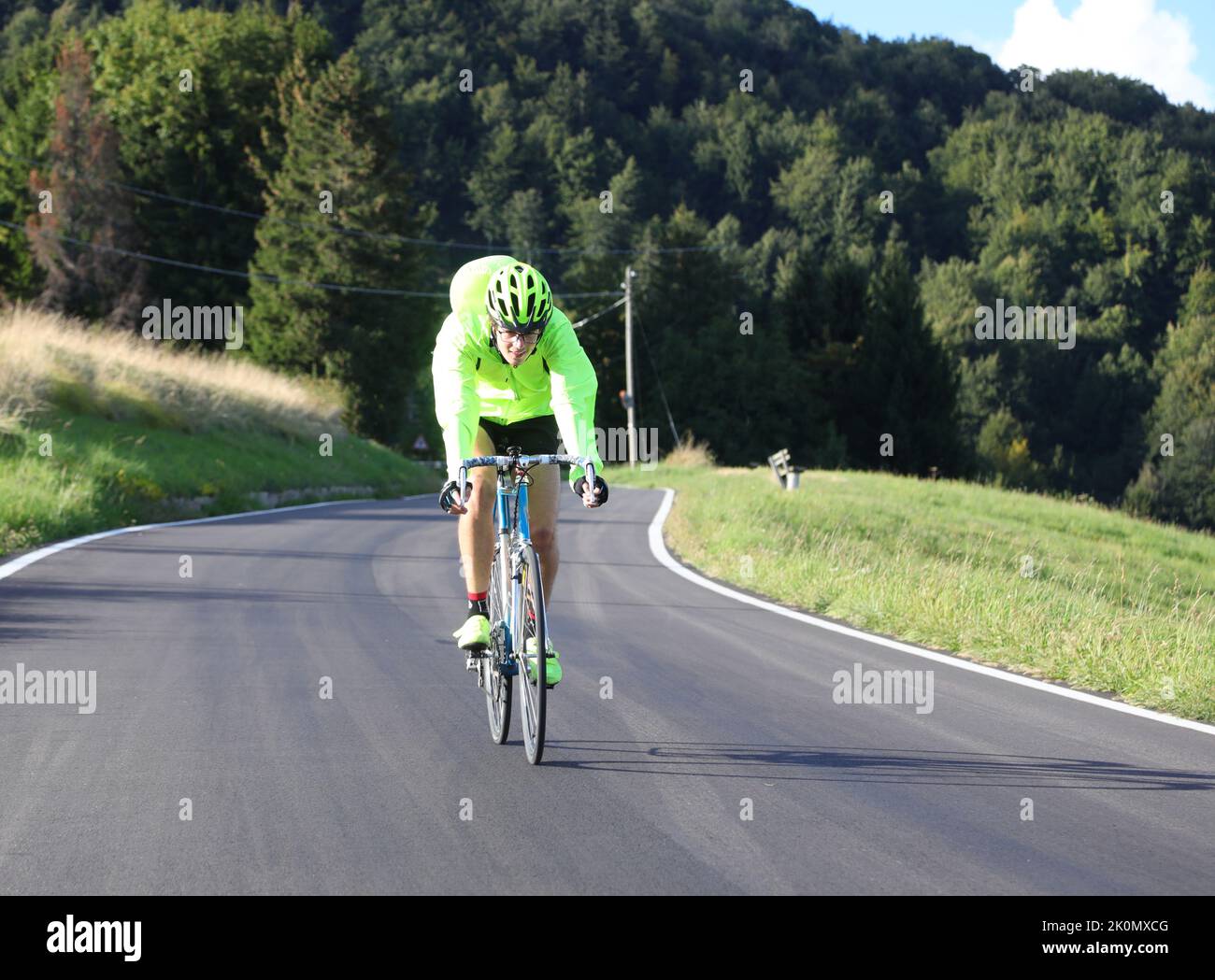 young cyclist with racing bicycle and phosphorescent waterproof jacket on a mountain road Stock ...