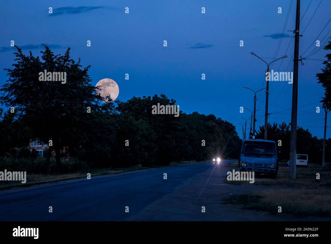 Moonrise in the evening over a country road Stock Photo - Alamy