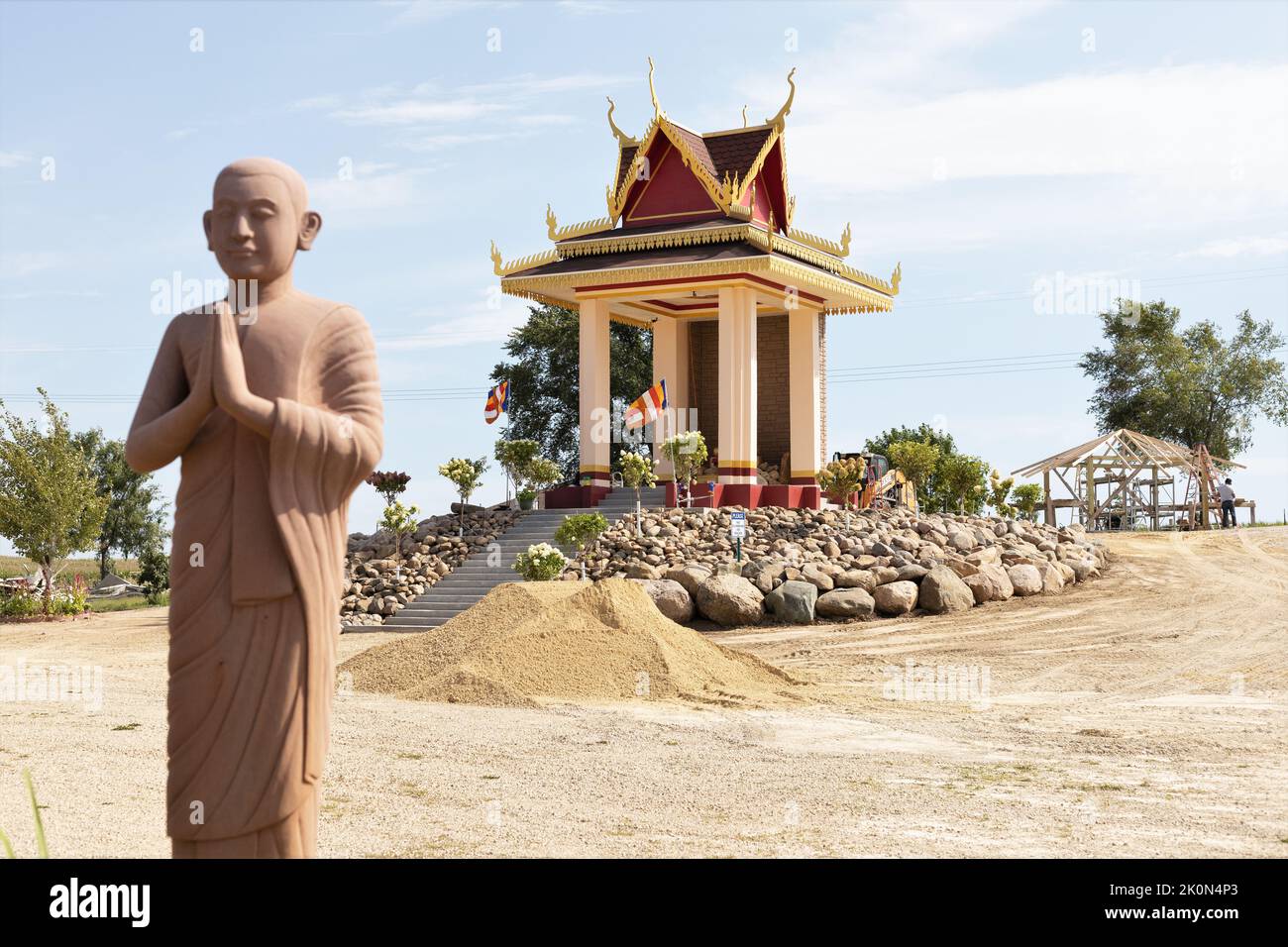 A monk statue, a temple, and a building under construction, at Watt ...