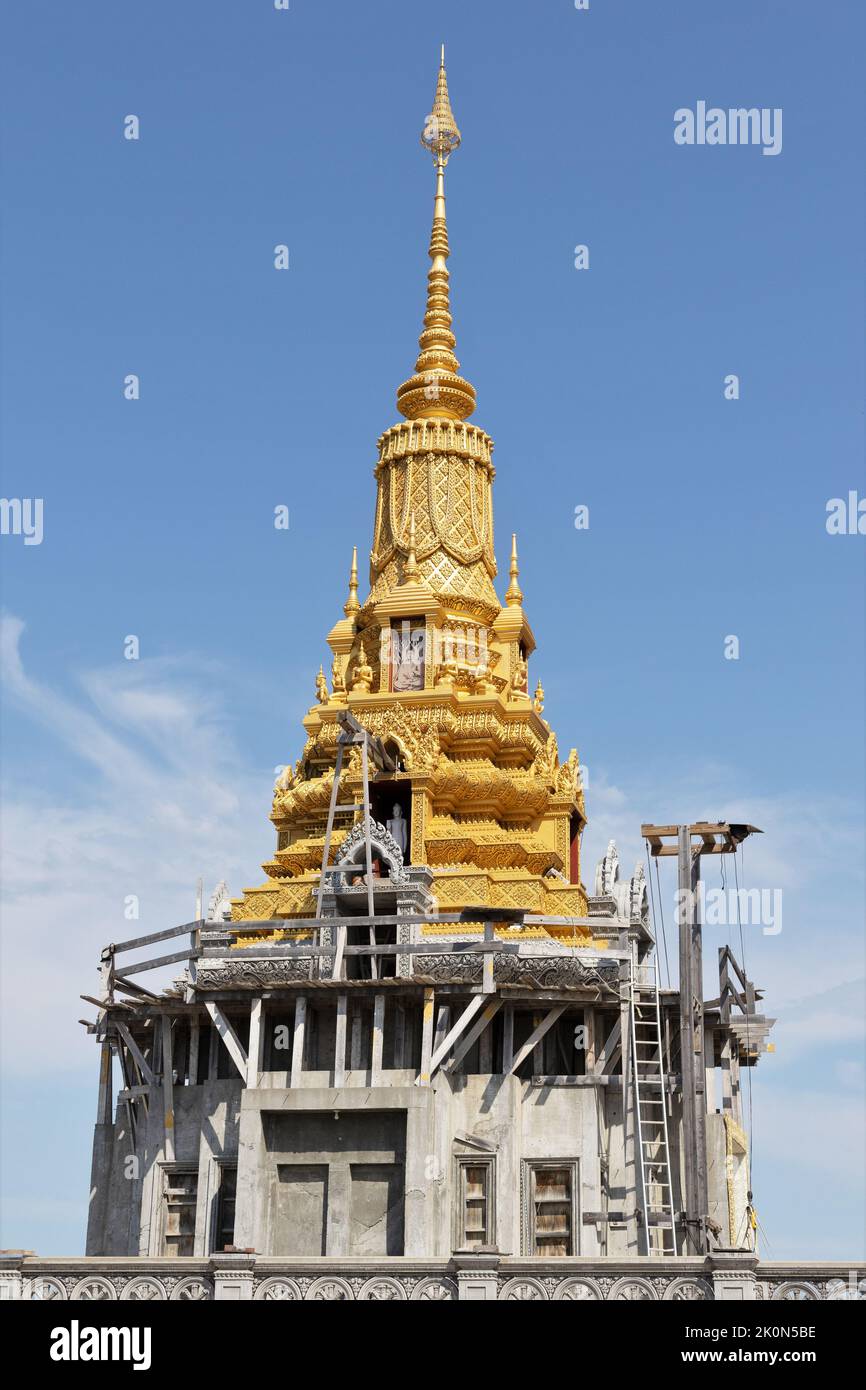 A partially finished temple with gold spire under construction at Watt ...