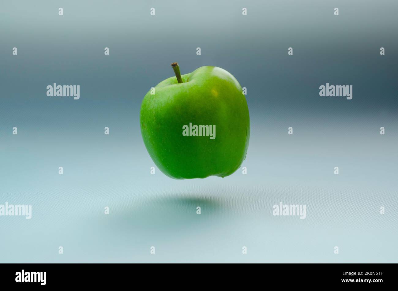 One green apple on a light blue background with a minimalistic ...