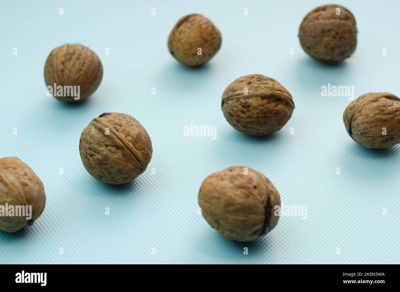 Walnuts laid in diagonal pattern on turquoise blue background. Top down ...