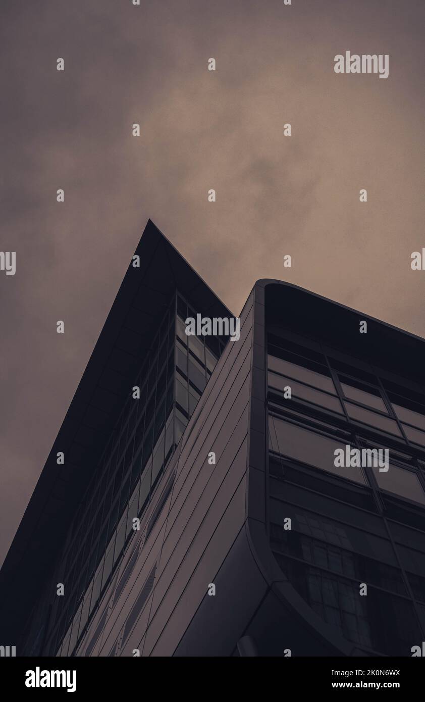A vertical and low-angle shot of a modern building on a cloudy day ...