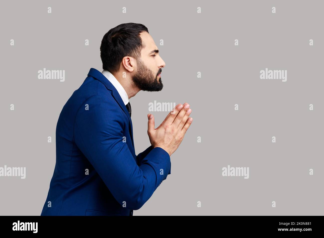 Side view of man holding hands in prayer, looking with imploring ...