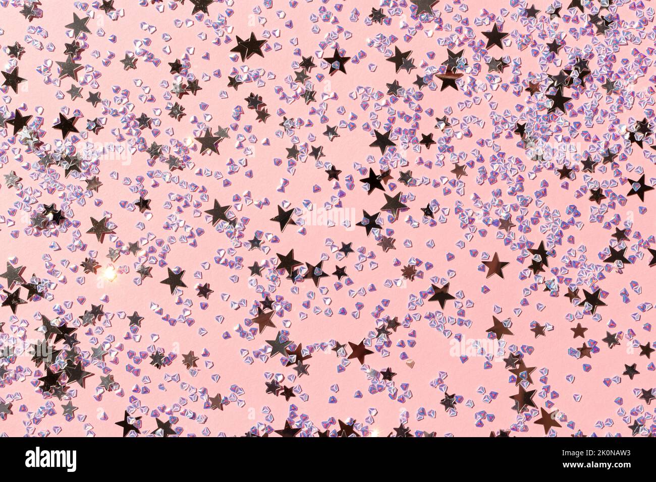 Silver stars and crystals confetti on a pink background. Glowing ...