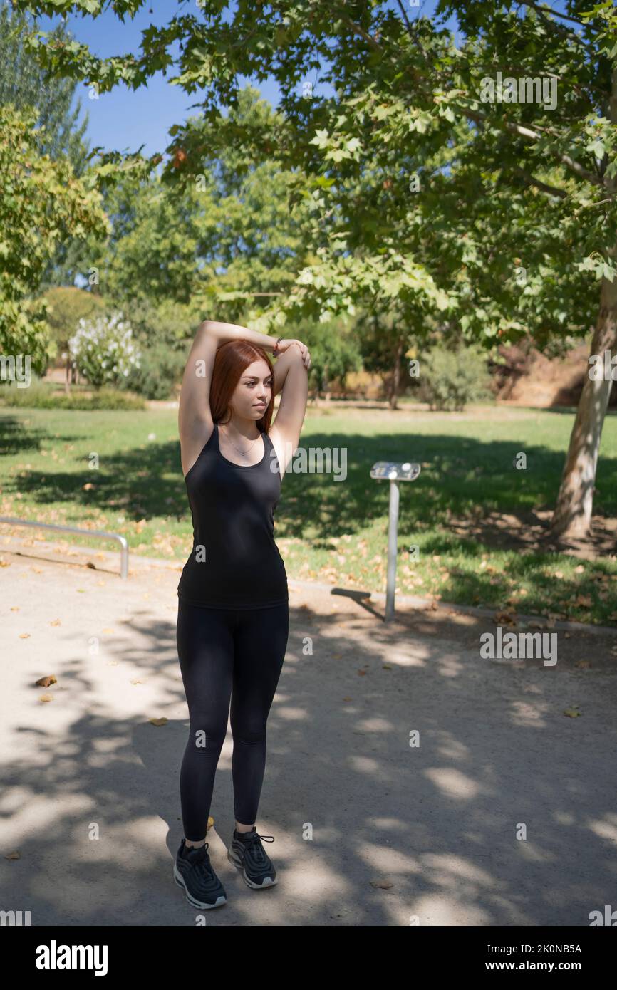 Fitness young redhead woman doing stretching exercise outdoors in public park Stock Photo - Alamy