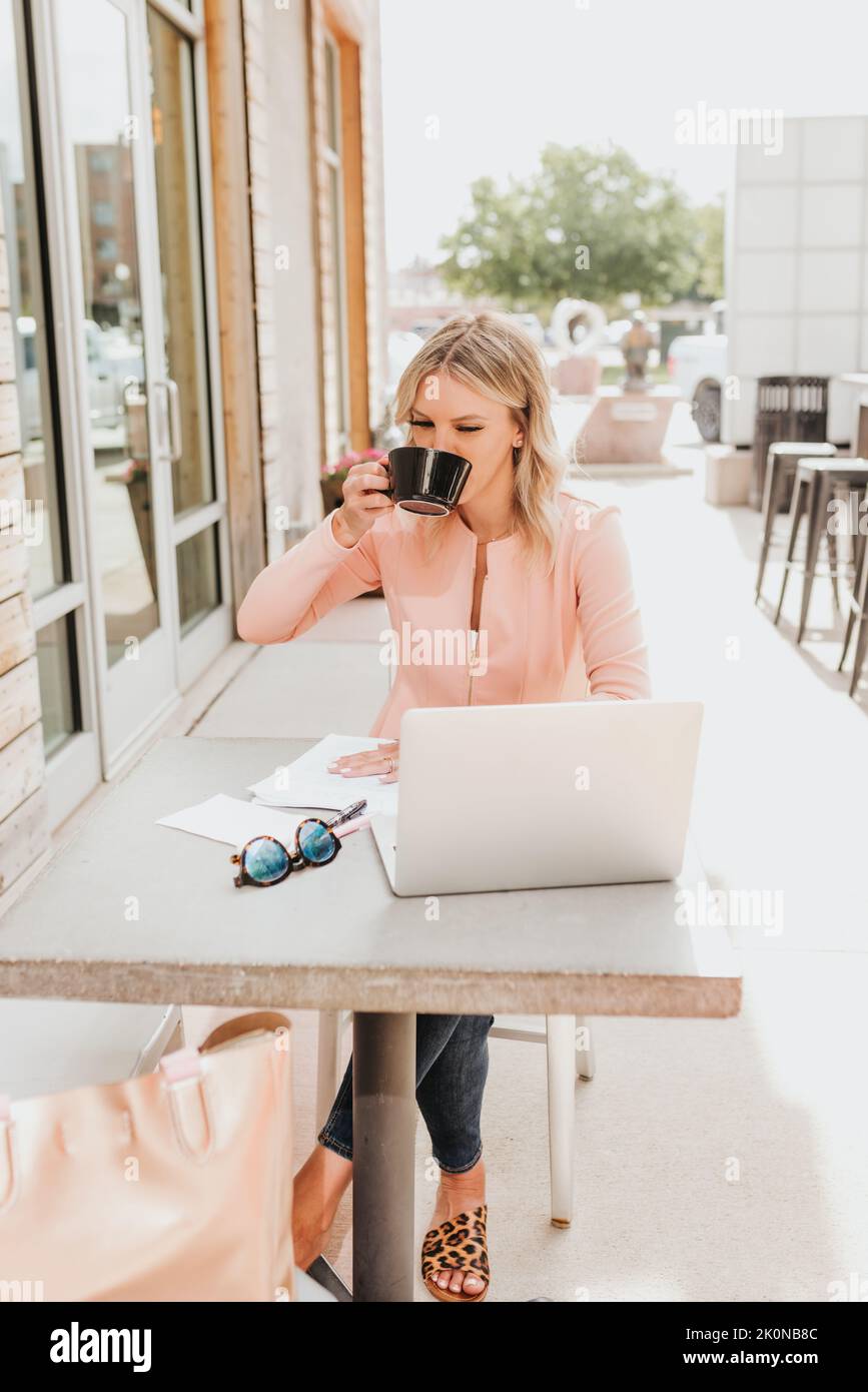 Young professional sips coffee while working on laptop outside Stock ...