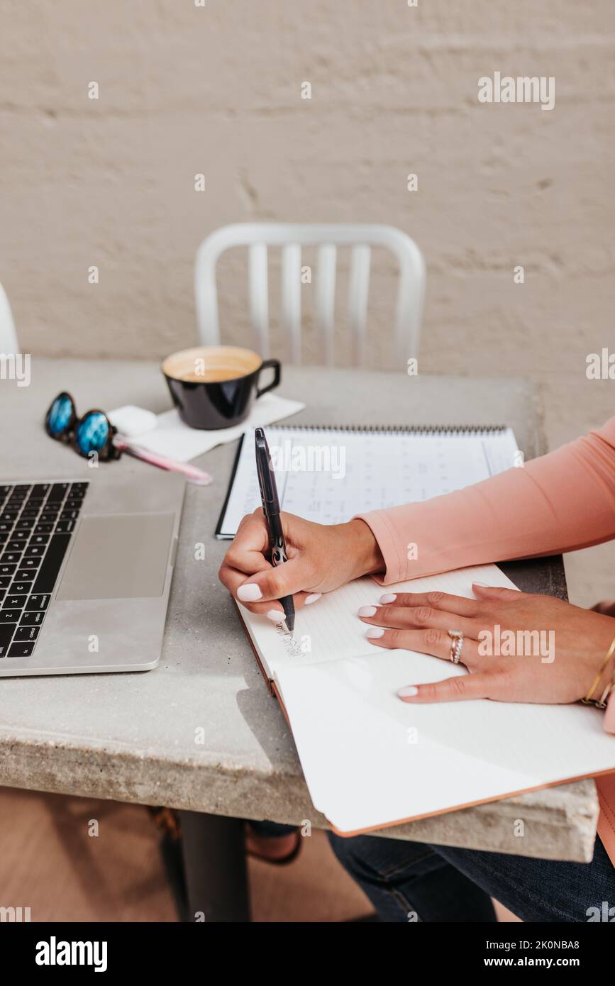 Three quarter view of young professional female writing in notebook ...