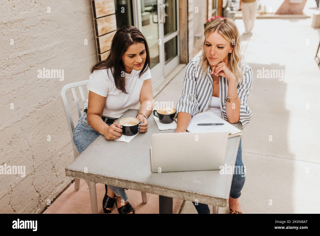 Two young female professionals work outside on laptop together Stock ...