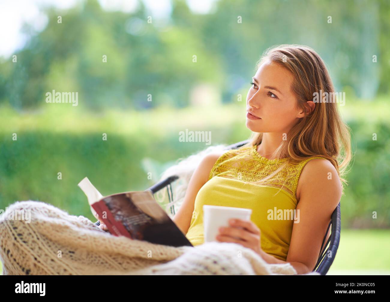 Relaxing with a good book. a young woman reading a book at home Stock ...
