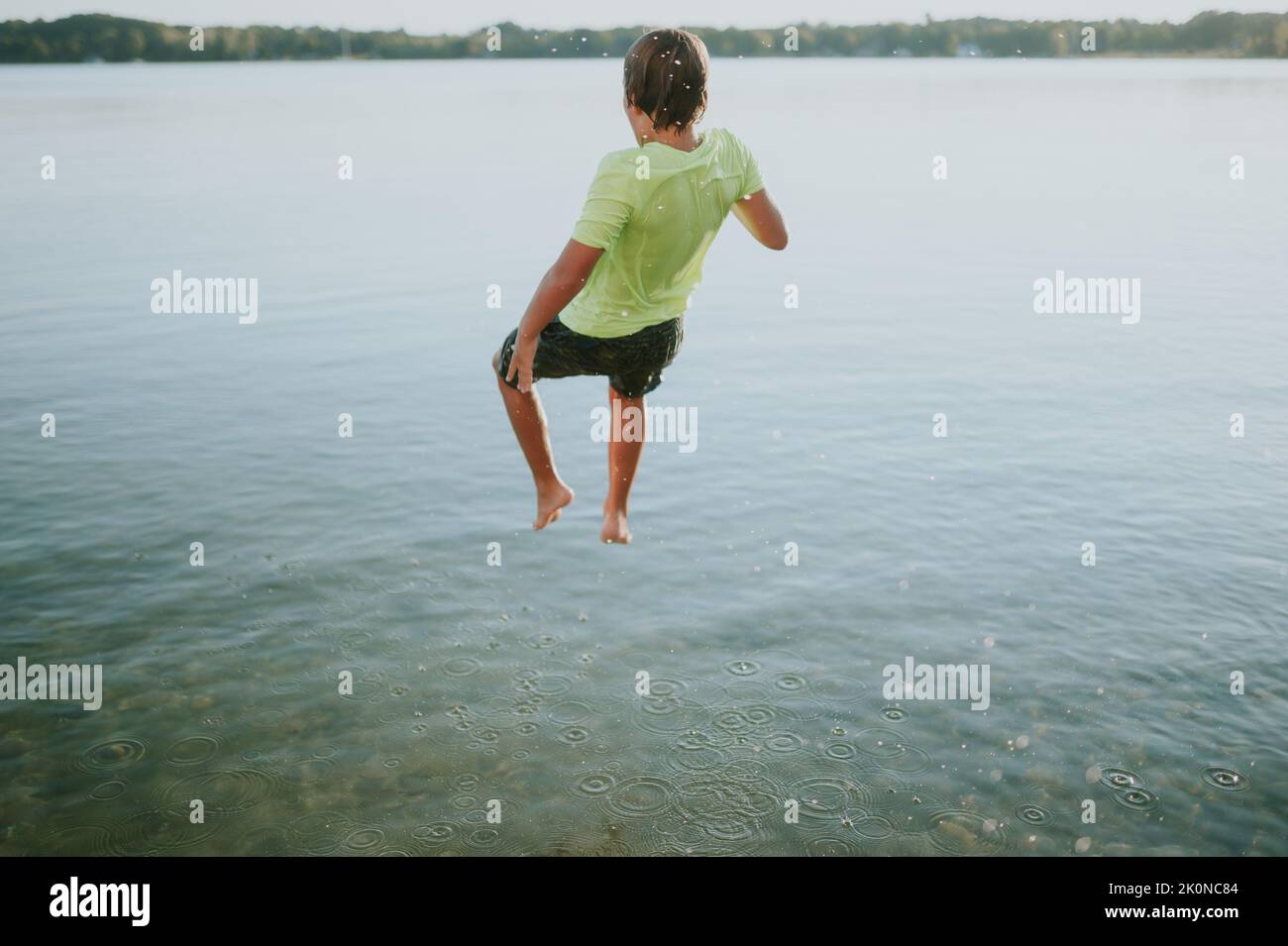 Full body view of boy in a midair jump above a lake for swimming Stock ...