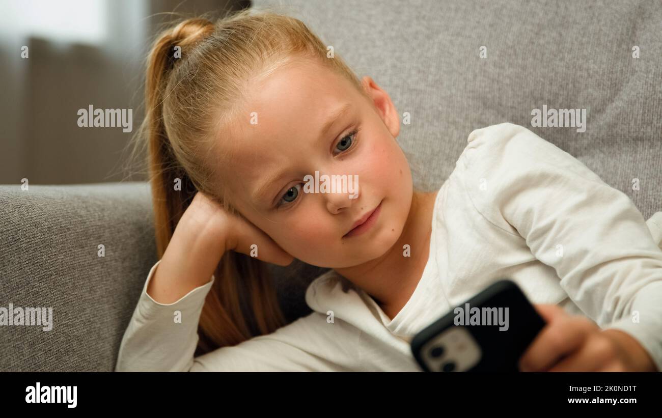 Relaxed blonde child little girl blogger cute kid teen resting on couch ...
