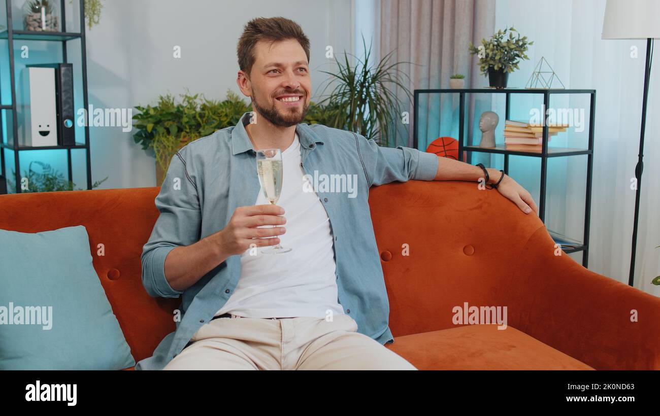 Joyful caucasian adult man hold glass of champagne cheering drinking ...