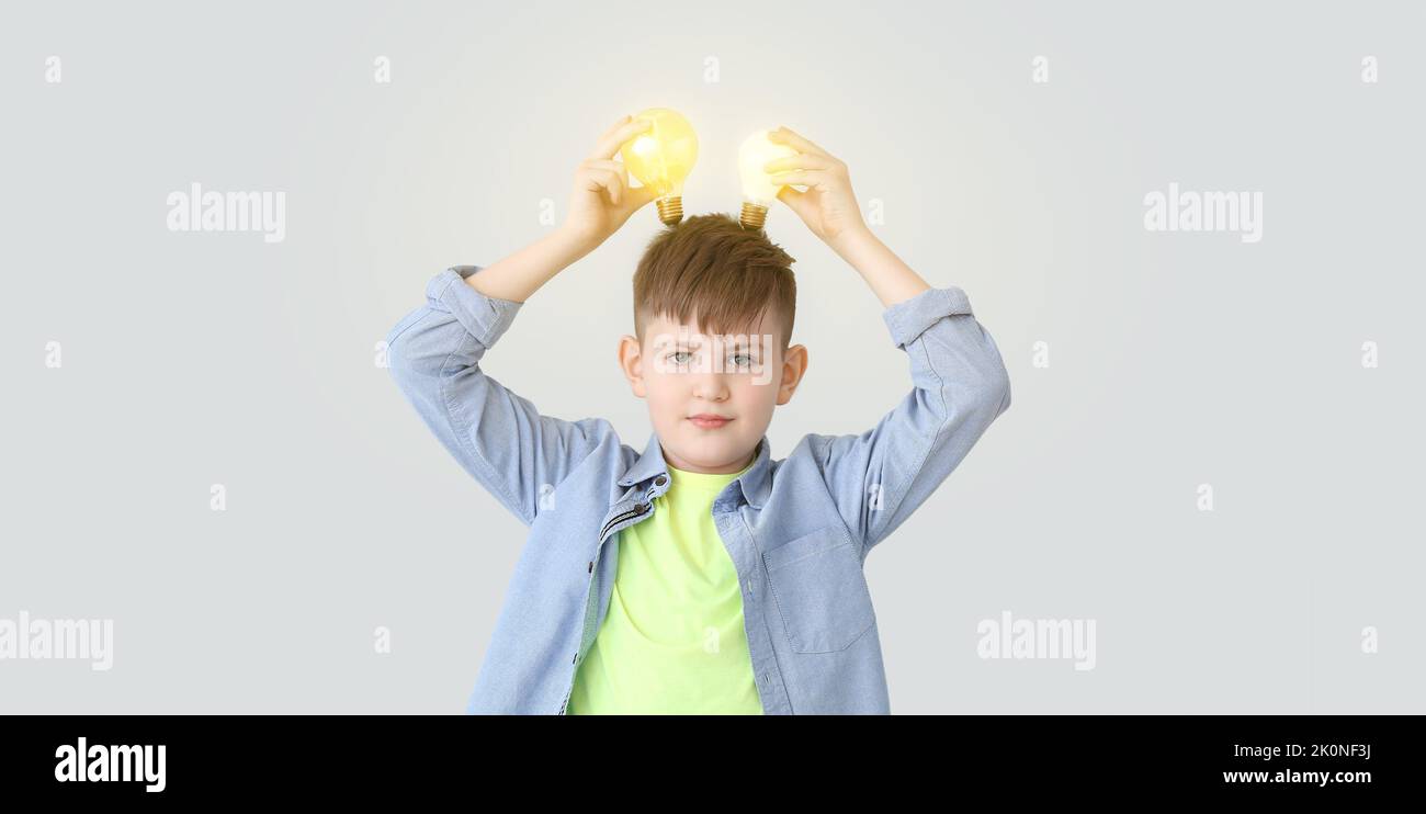 Cute little boy with glowing light bulbs on grey background Stock Photo ...