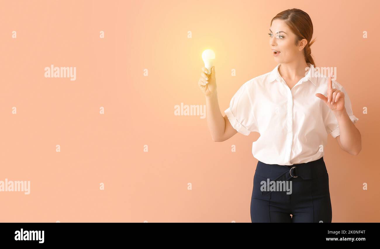 Surprised businesswoman with light bulb on pink background. Concept of ...