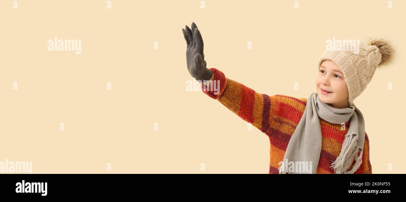 Cute little boy in warm clothes on beige background with space for text ...