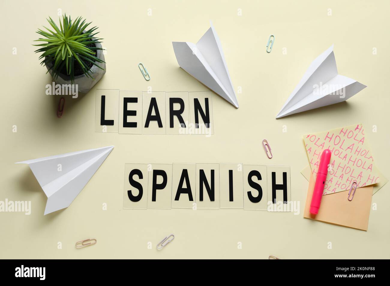 Text LEARN SPANISH, stationery, flowerpot and paper planes on beige ...