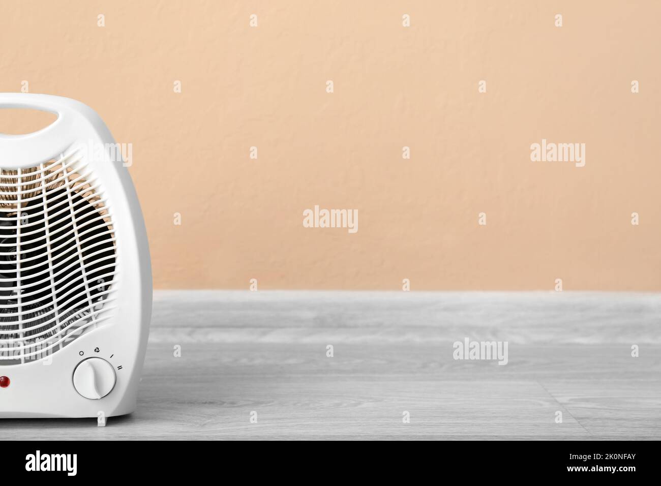 Electric fan heater near beige wall Stock Photo - Alamy