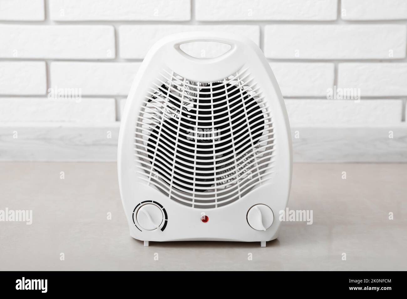Electric fan heater near white brick wall Stock Photo - Alamy