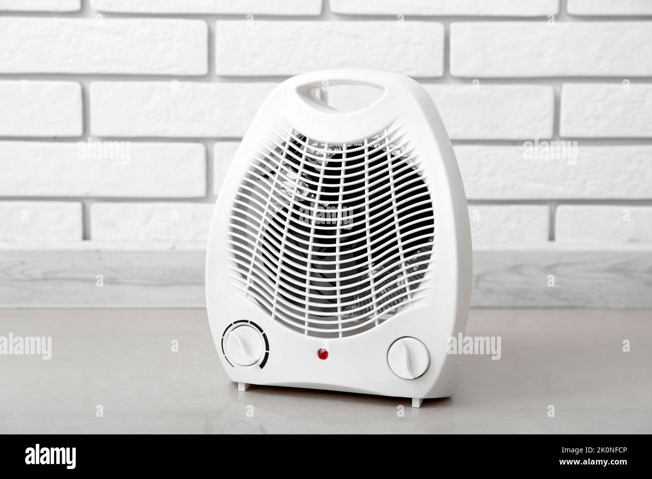 Electric fan heater near white brick wall Stock Photo - Alamy