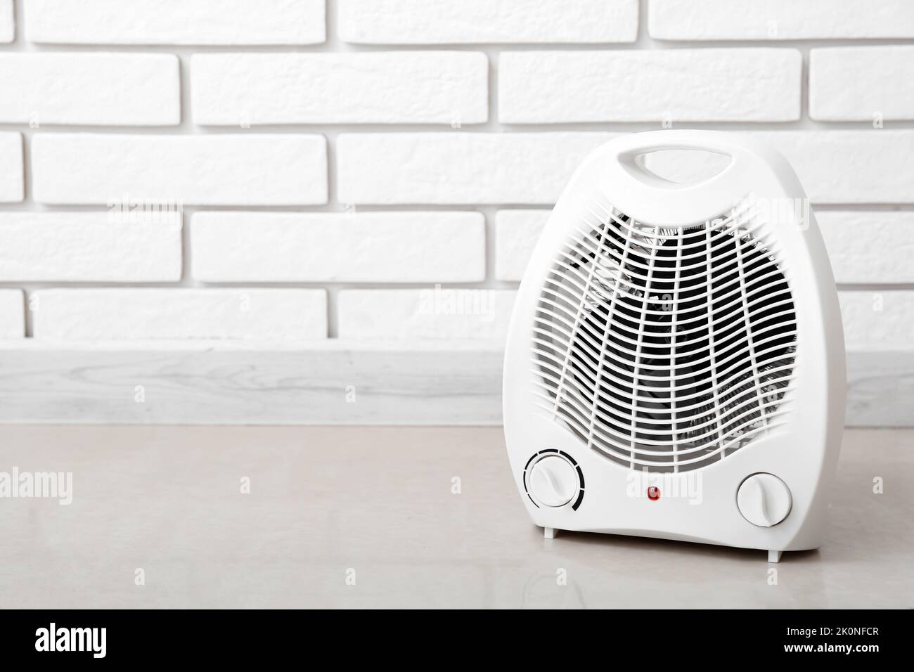 Electric fan heater near white brick wall Stock Photo - Alamy