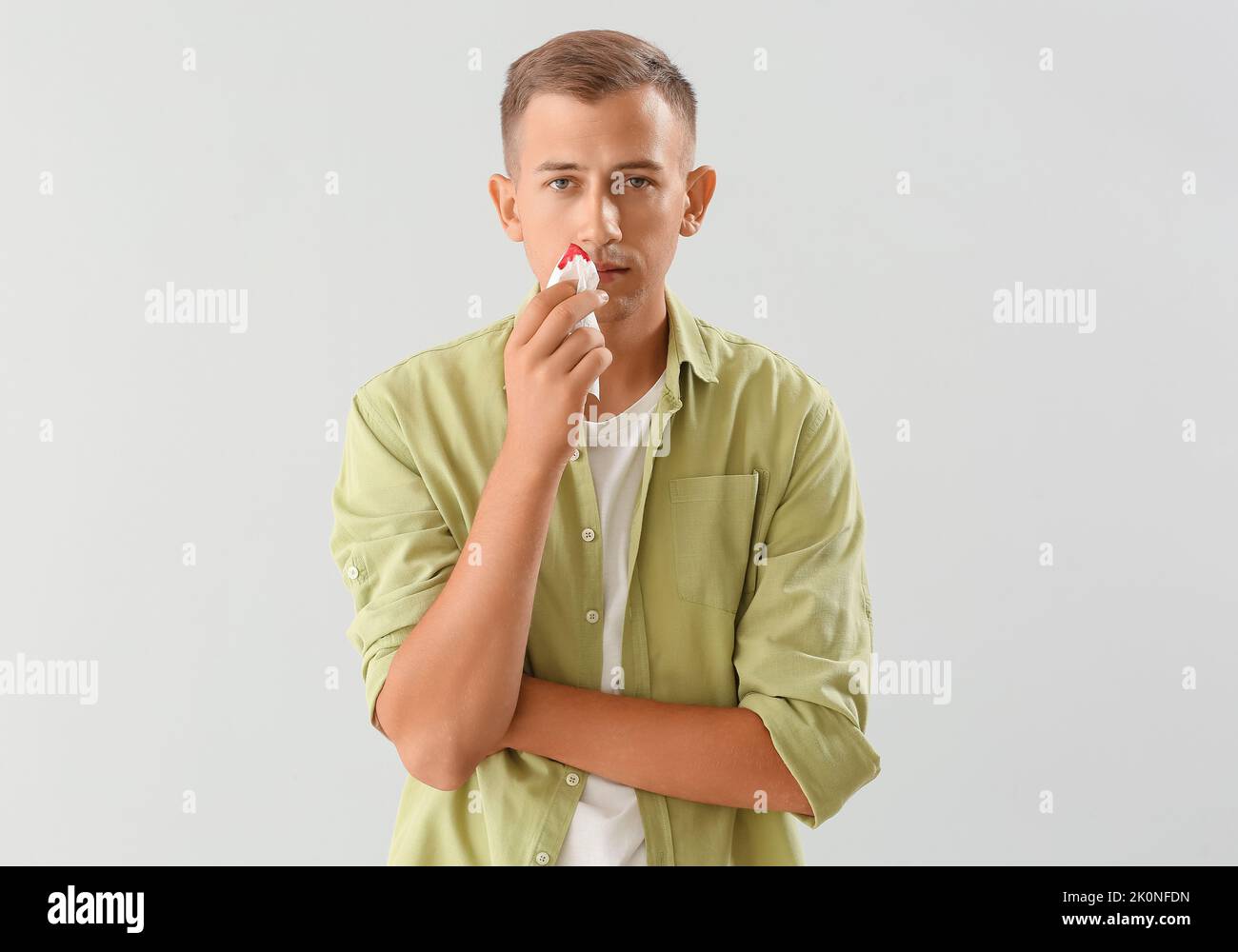 Young man with nosebleed and tissue on white background Stock Photo - Alamy