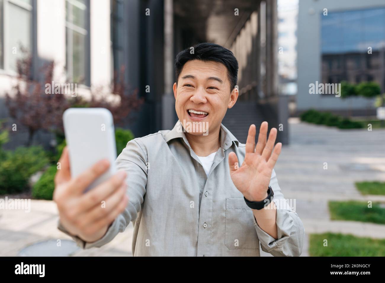 Positive korean man using smartphone making video call, walking in the ...