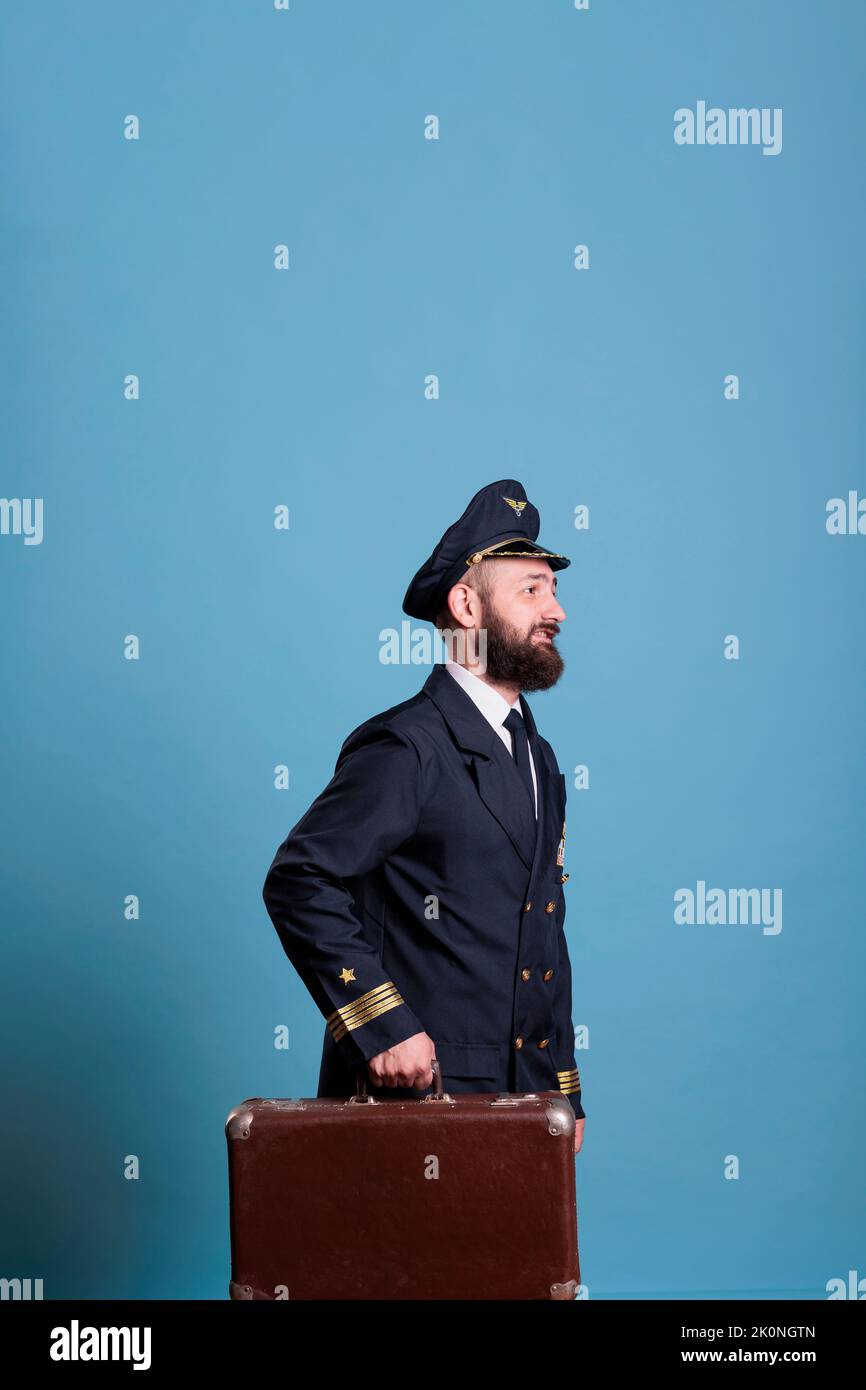 Airplane pilot in professional airline uniform walking with luggage ...