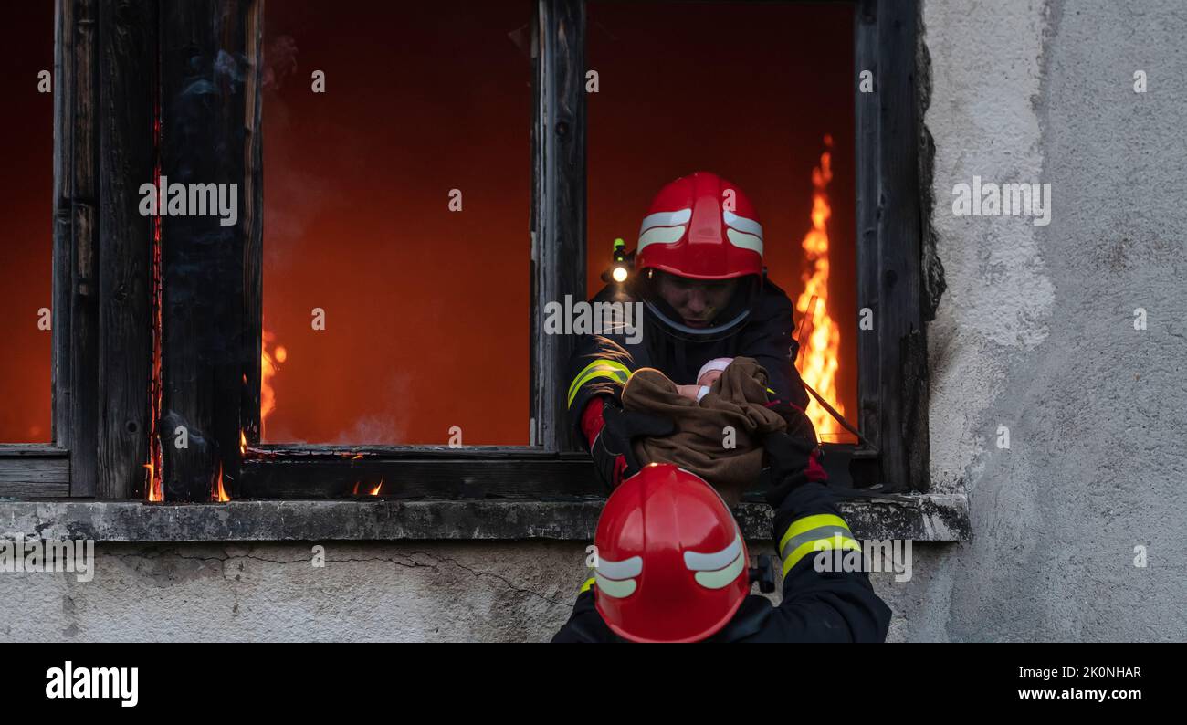 Firefighter hero carrying baby girl out from burning building area from ...