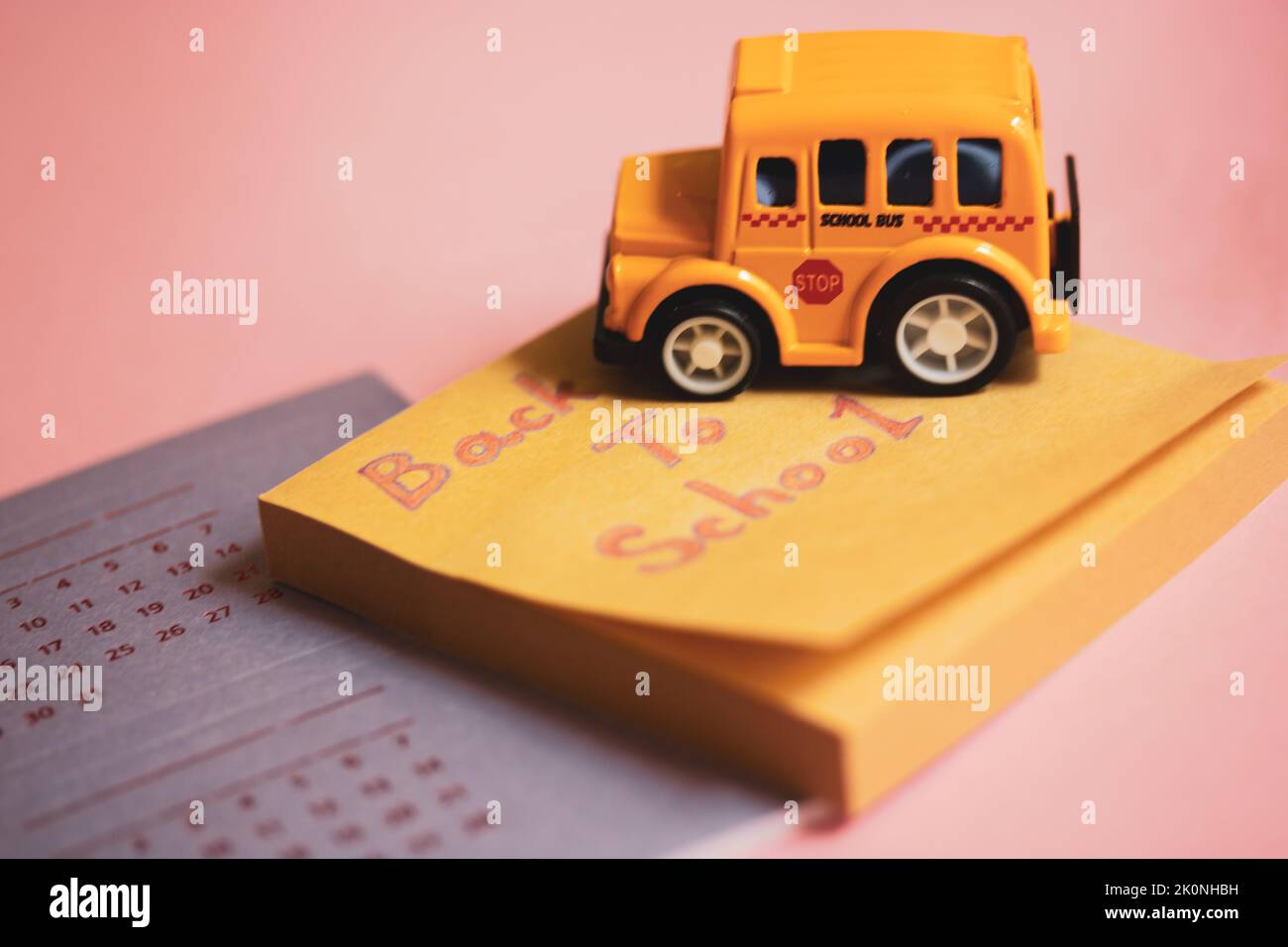 Toy yellow American school bus on table, calendar with dates, colorful ...