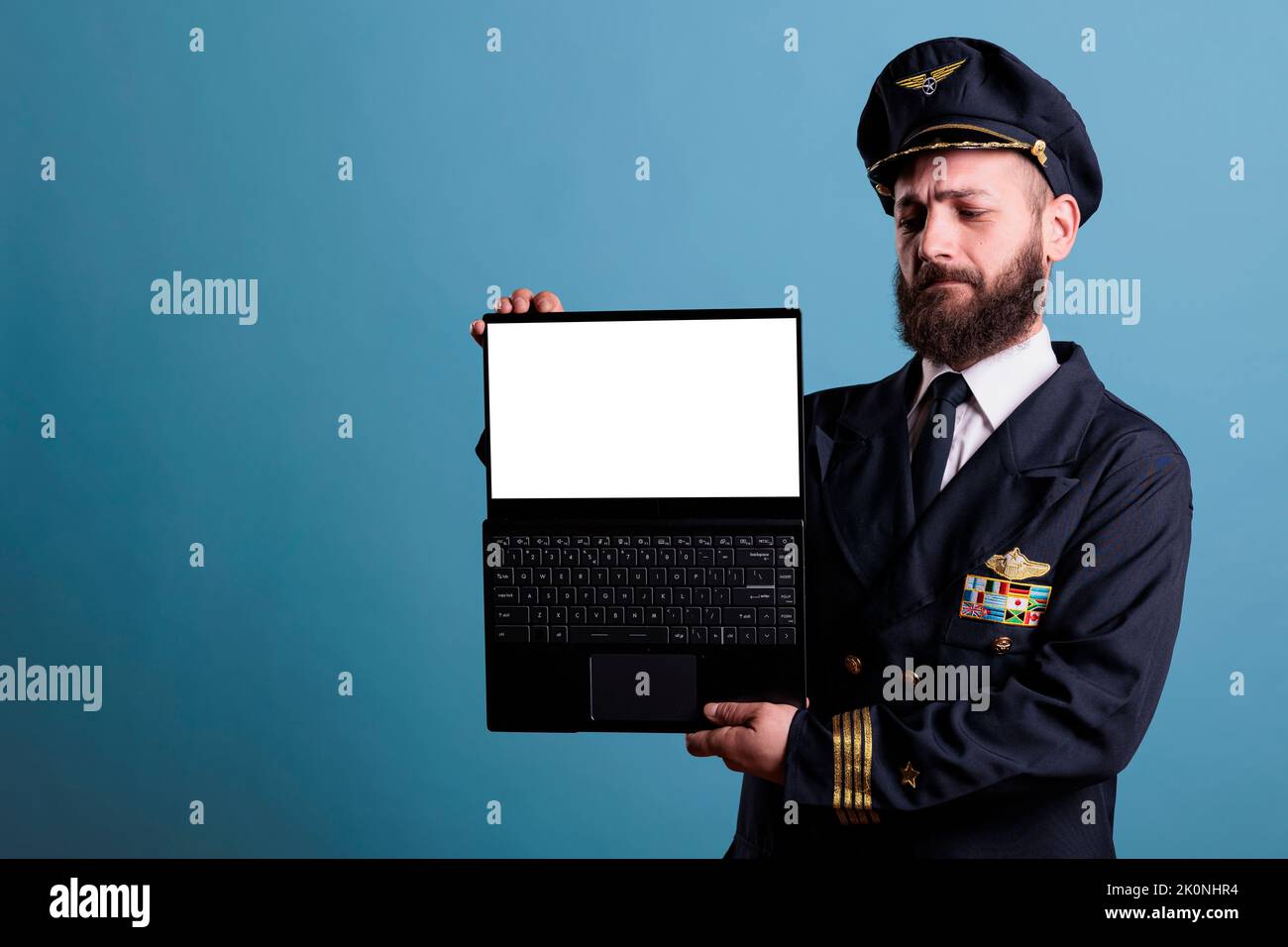 Serious airplane pilot showing laptop with empty white screen, aviation ...