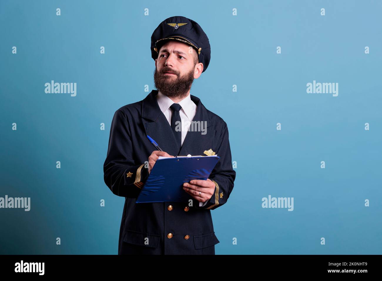 Airplane captain holding clipboard, filling documents, concentrated ...