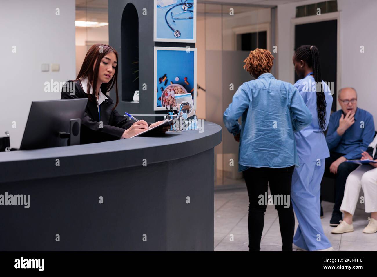 Female receptionist checking report files at hospital reception desk ...
