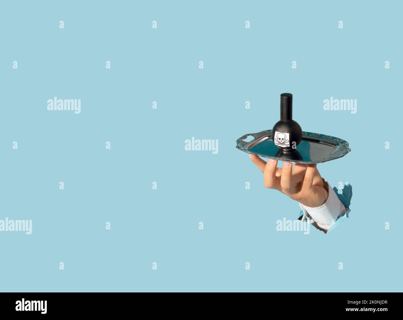 Man's hand holding black bottle with poison and warning sign on plate ...