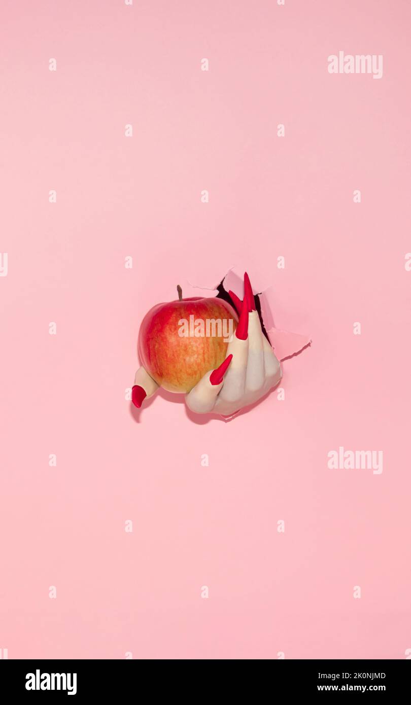 Witch hand holding red apple as symbol of temptation, poison. Pastel ...