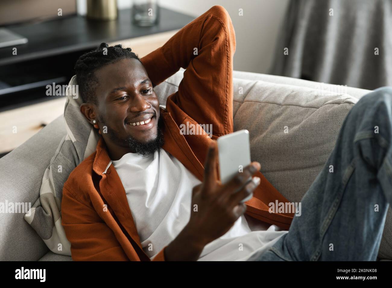 Cheerful african american man watching video on smartphone, resting and ...