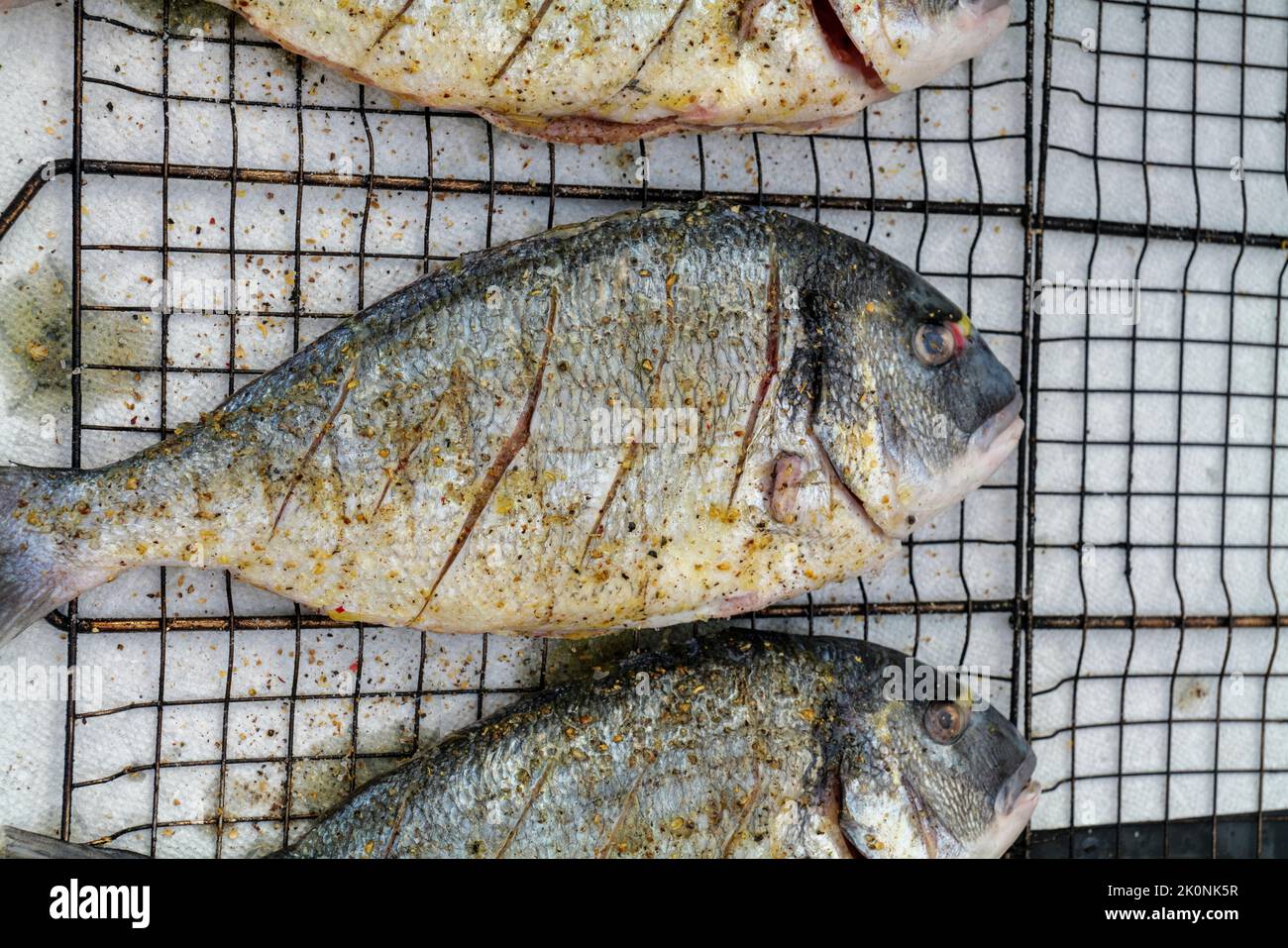 Grilling process of dorado fish on a charcoal BBQ grill in the backyard ...