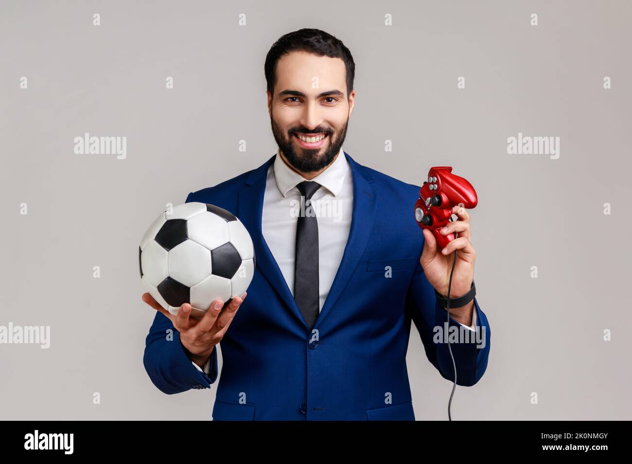 Delighted handsome bearded man holding joypad and soccer black and ...