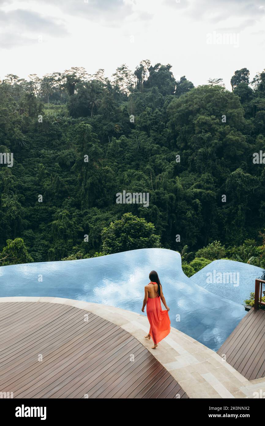 Aerial shot of young woman walking by the pool. Woman near swimming ...