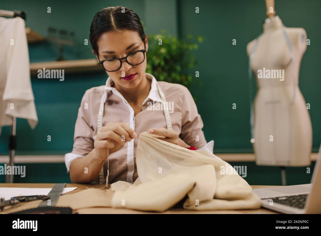 Female designer hand stitching dress in fashion studio. Asian woman ...