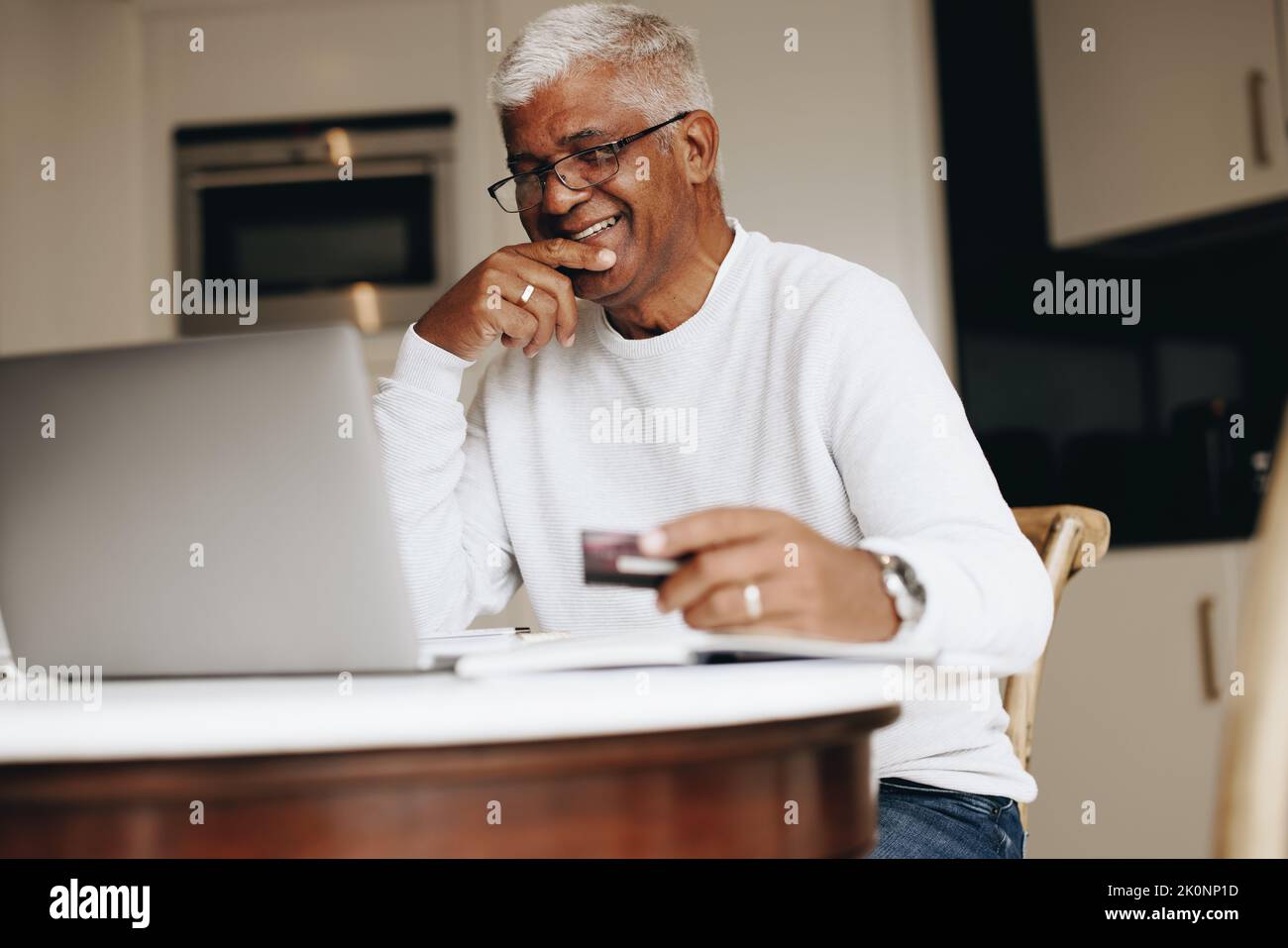 Carefree senior man smiling cheerfully while shopping online at home ...