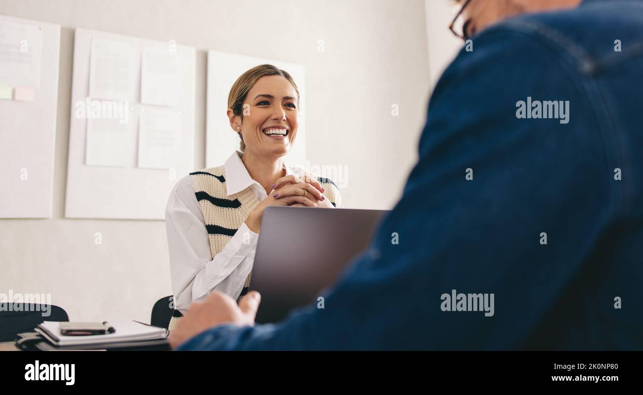 Cheerful businesswoman smiling during a meeting with a business partner ...