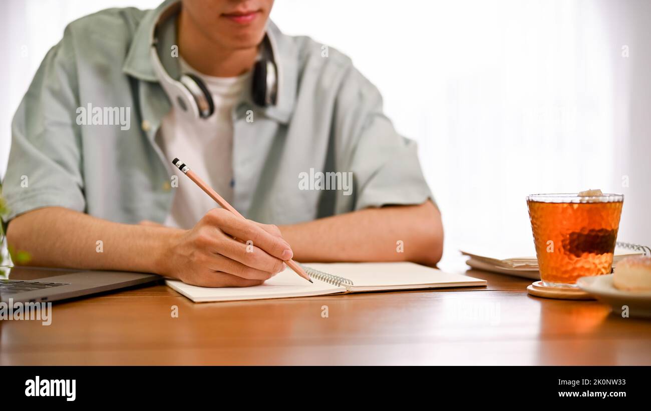 Smart young Asian male college student doing his homework, writing ...
