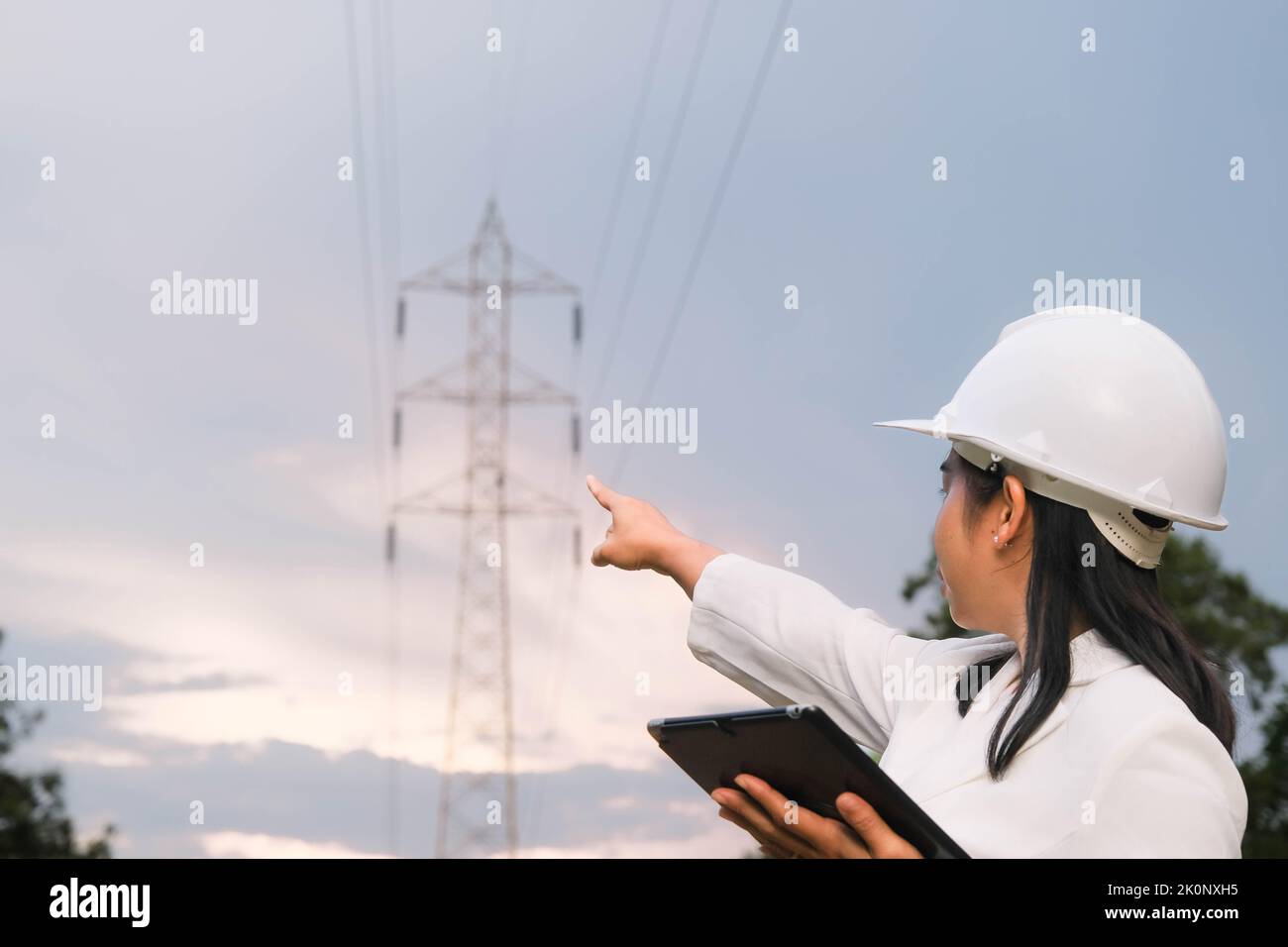 Asian female electrical engineer working on laptop near high voltage ...